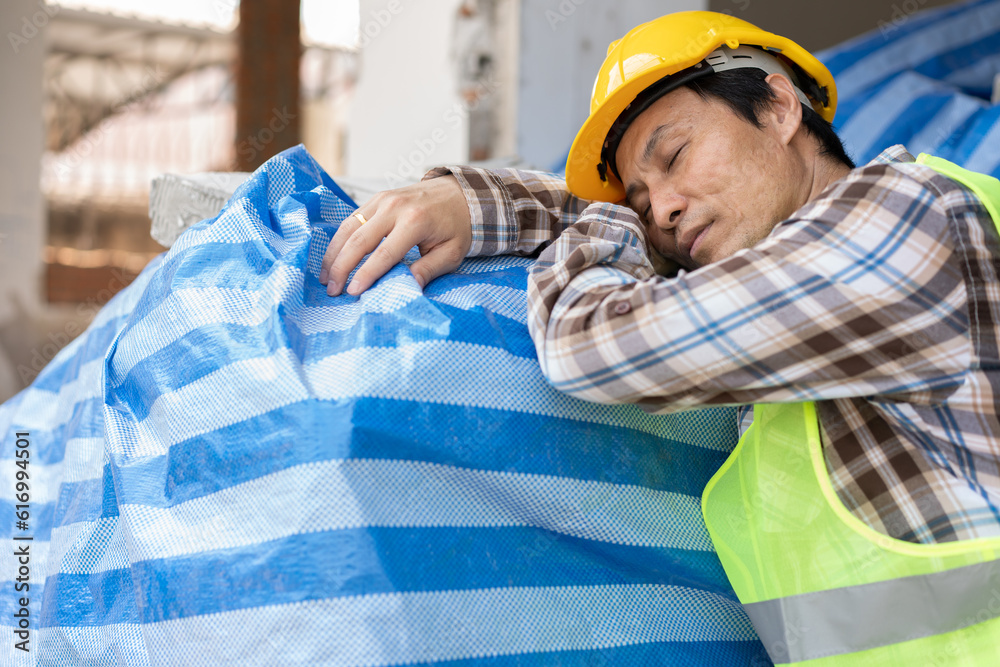 Construction worker with white safety helmet take a nap because so are tired from working in the ...