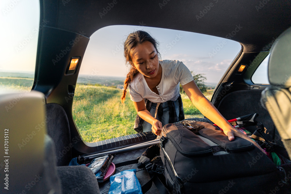 young adventurer adjusts her equipment before - after hiking in her car ...