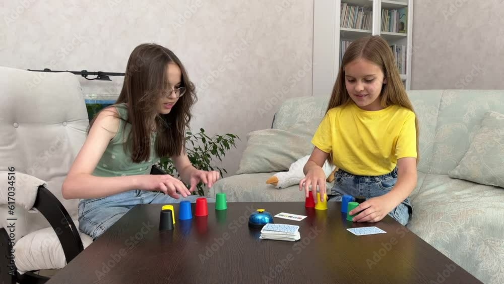 two girls are playing a board game with colorful figures and cards. The ...