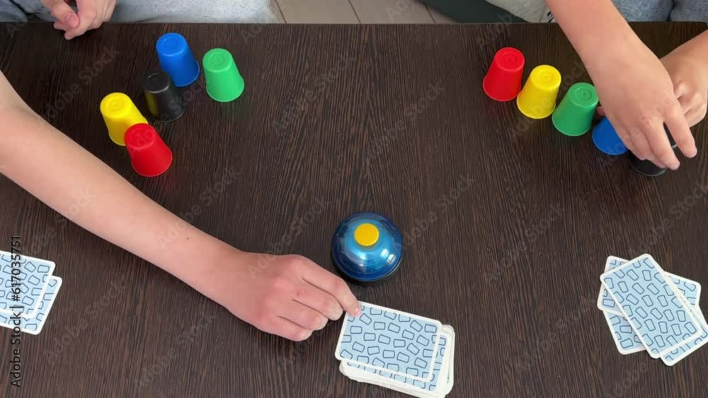 two girls are playing a board game with colorful figures and cards. The ...