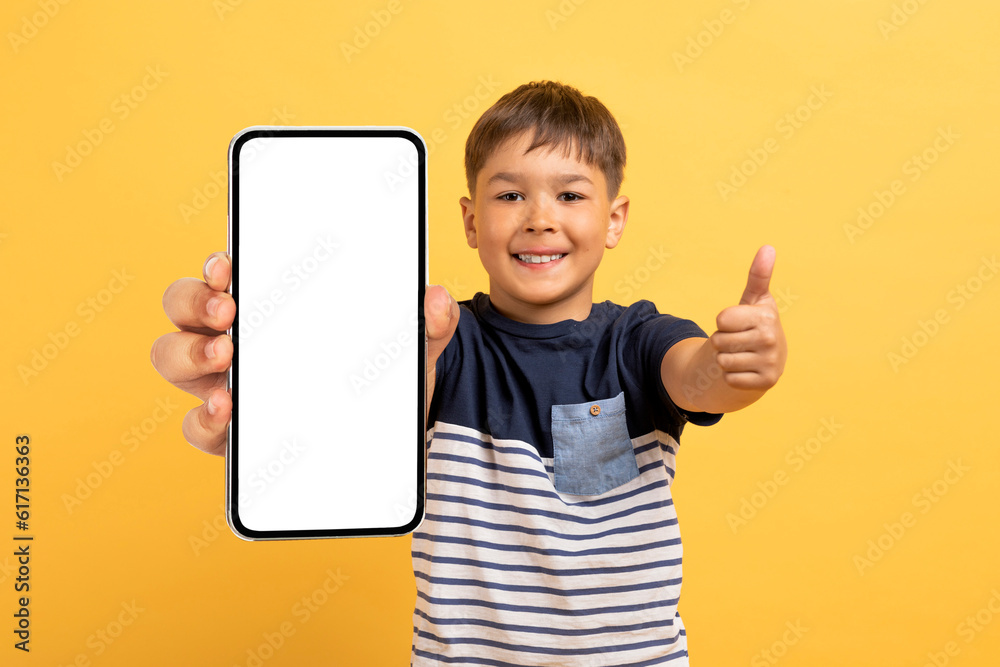 Cheerful boy showing smartphone with white screen, thumb up Stock Photo ...