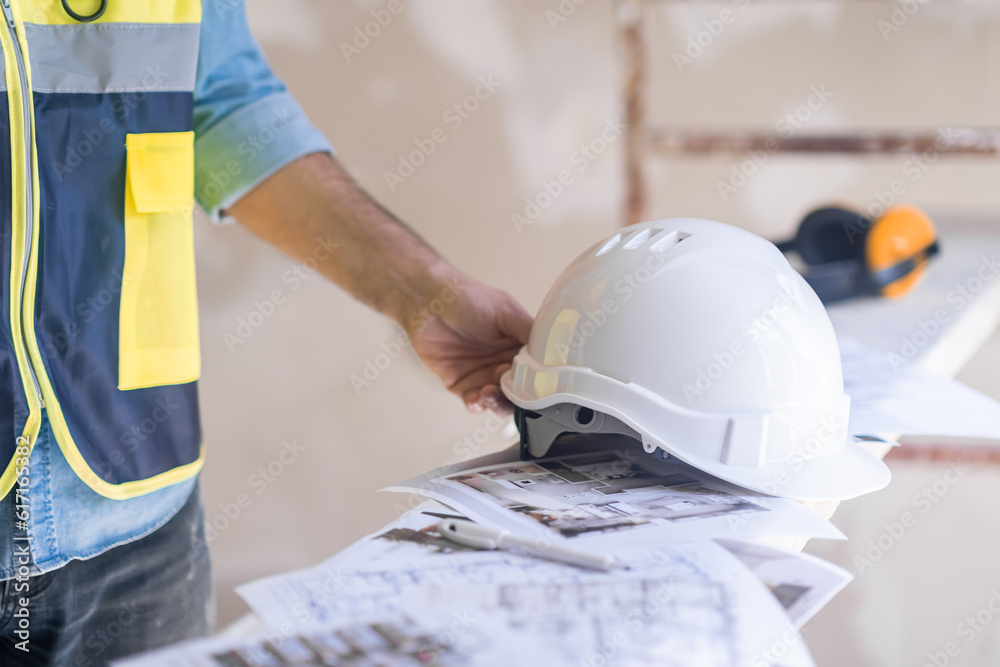 Architect reaching hand to take hardhat on heap of project papers at ...