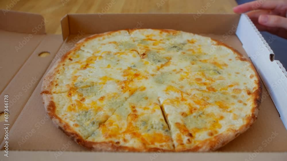 flat lay - female opening white box with 4 cheese pizza. side view ...