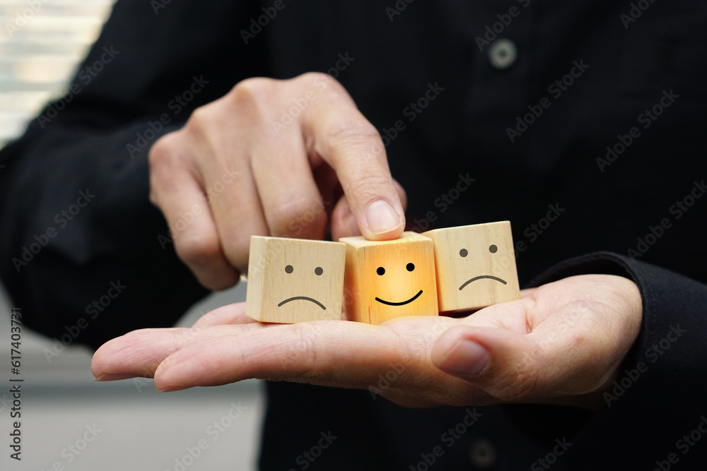 Businessman holding smiling and non-smiling face icons which print ...