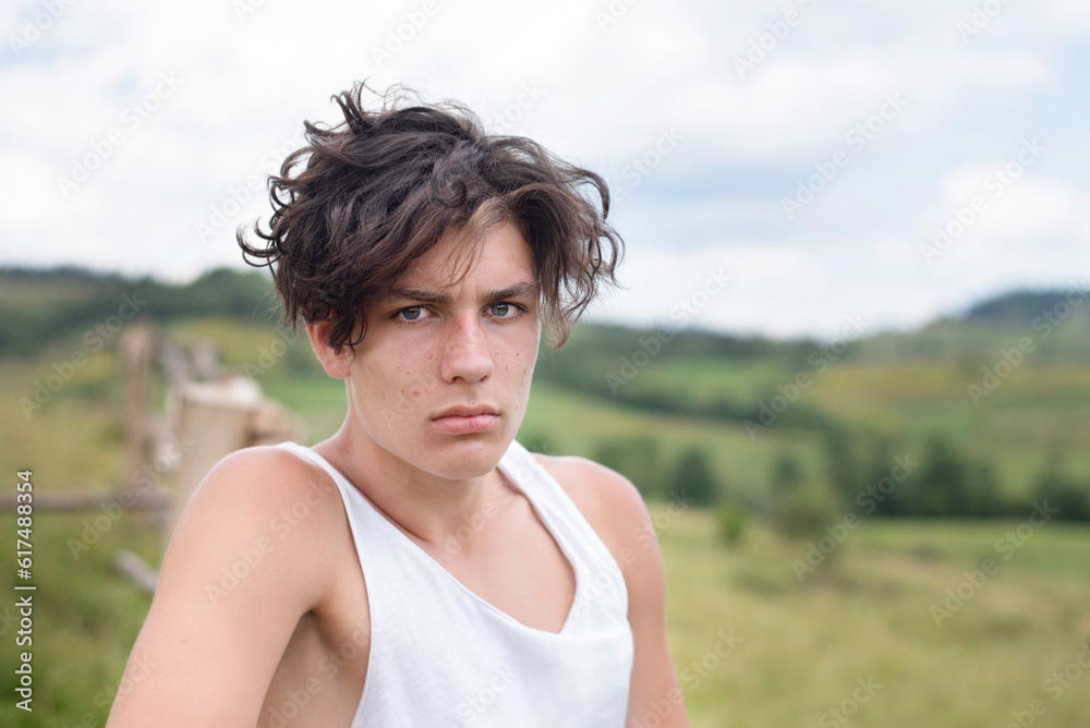 A teenage boy with a cute face but with pimples on skin is ashamed ...