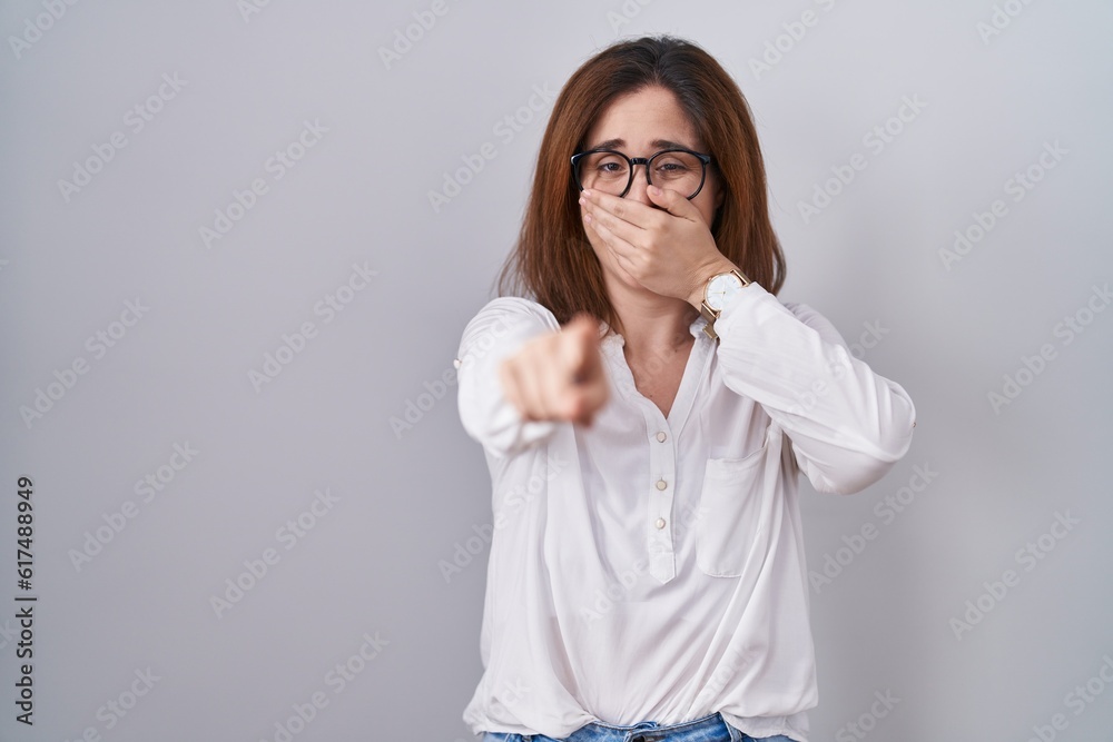Brunette woman standing over white isolated background laughing at you ...