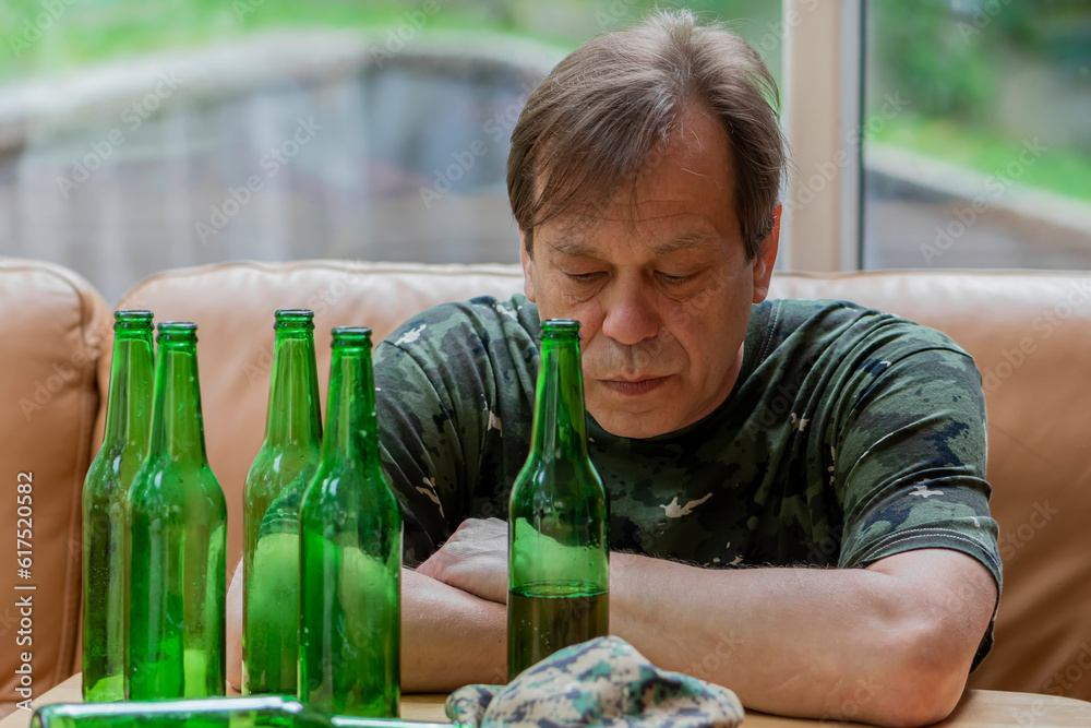 Elderly man in military uniform drinking beer, lots of empty bottles ...