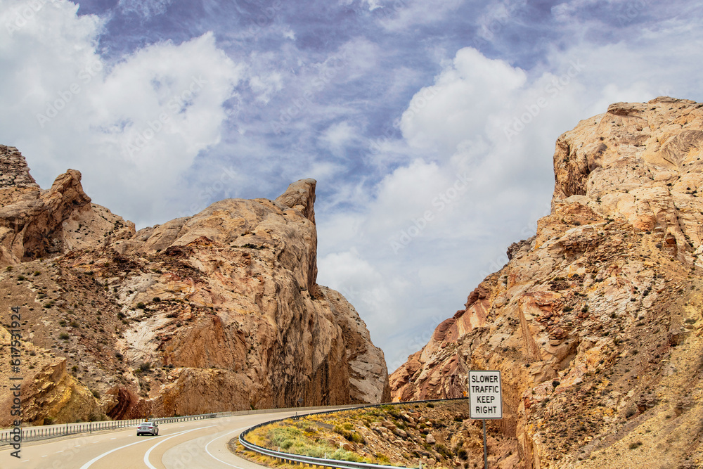 Highway cut through weirdly shaped barren mountains with car making ...