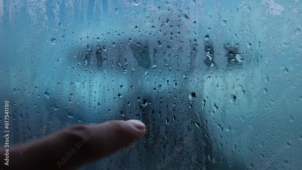 Closeup view of male caucasian finger drawing heart on window wet after ...