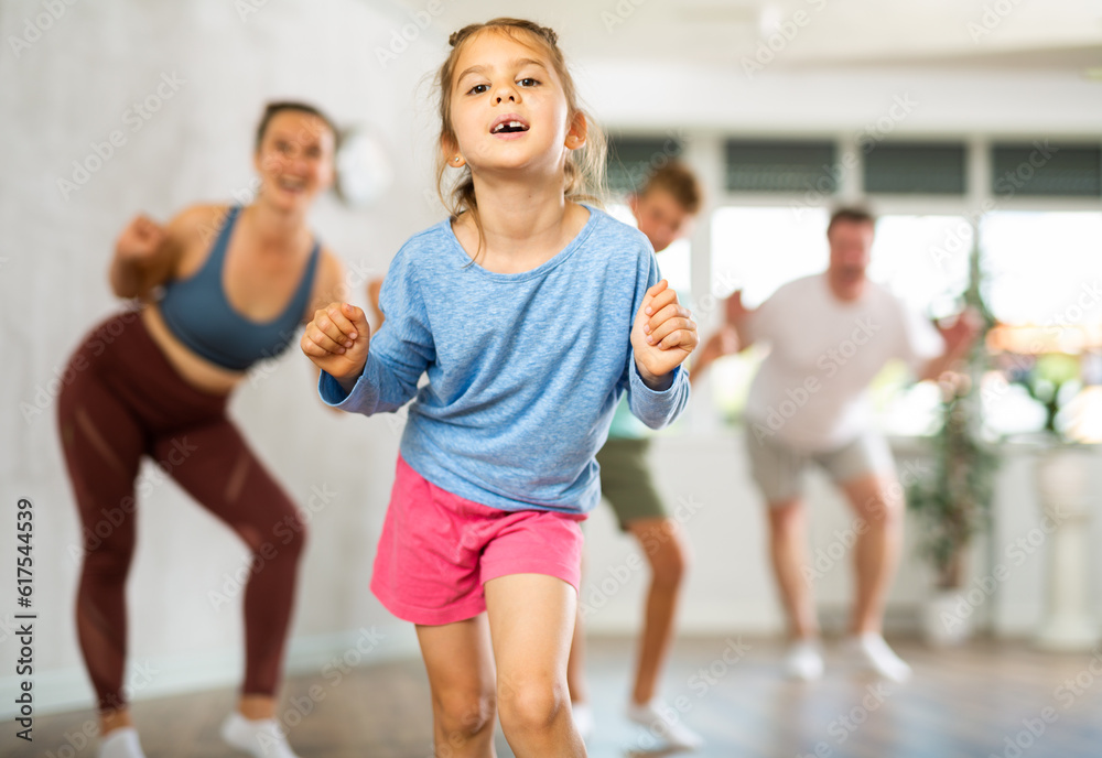 Cute little girl practicing dance movements together with her parents ...