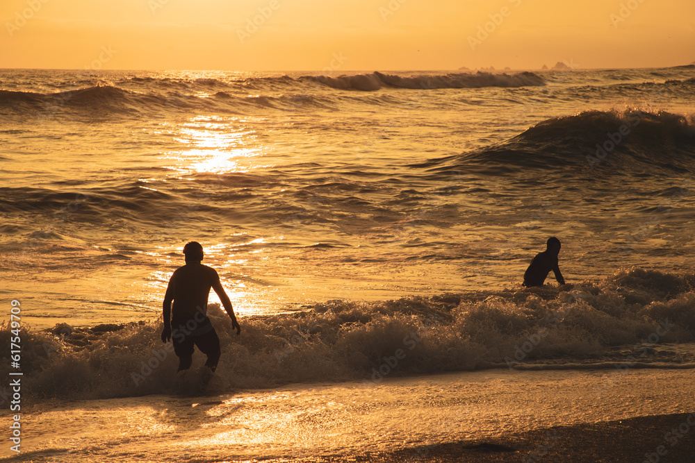 Foto de Personas a contraluz disfrutando de las olas del mar en la hora ...