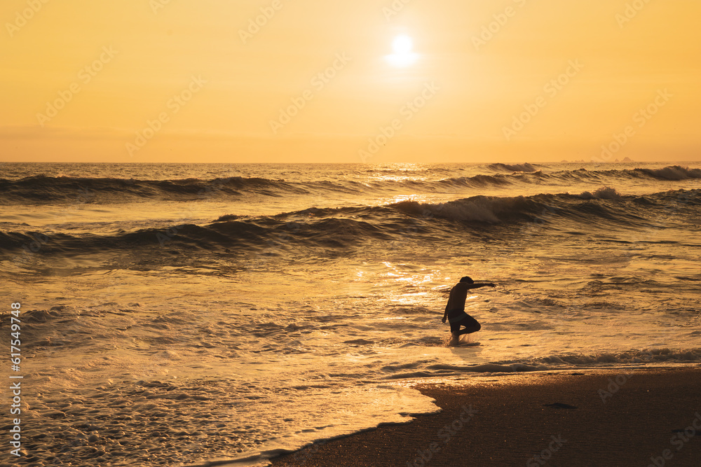 Personas a contraluz disfrutando de las olas del mar en la hora dorada ...