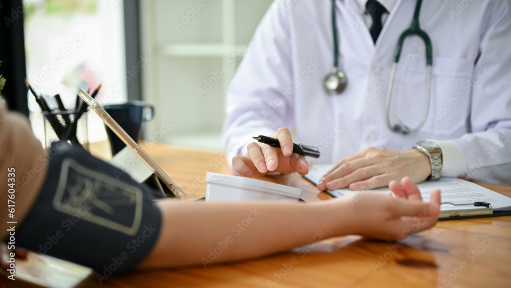 A male doctor examining a patient's heart rate and measuring blood ...