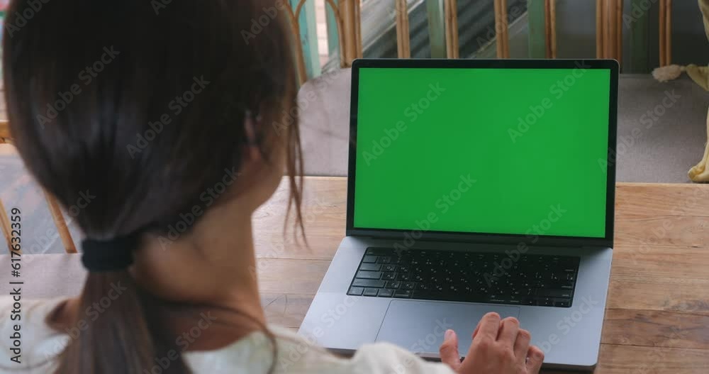Over the shoulder shot woman using laptop with green screen while ...