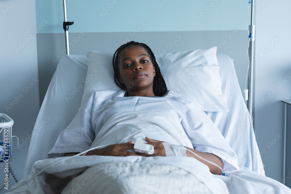 Portrait of african american female patient with braids, lying in bed ...