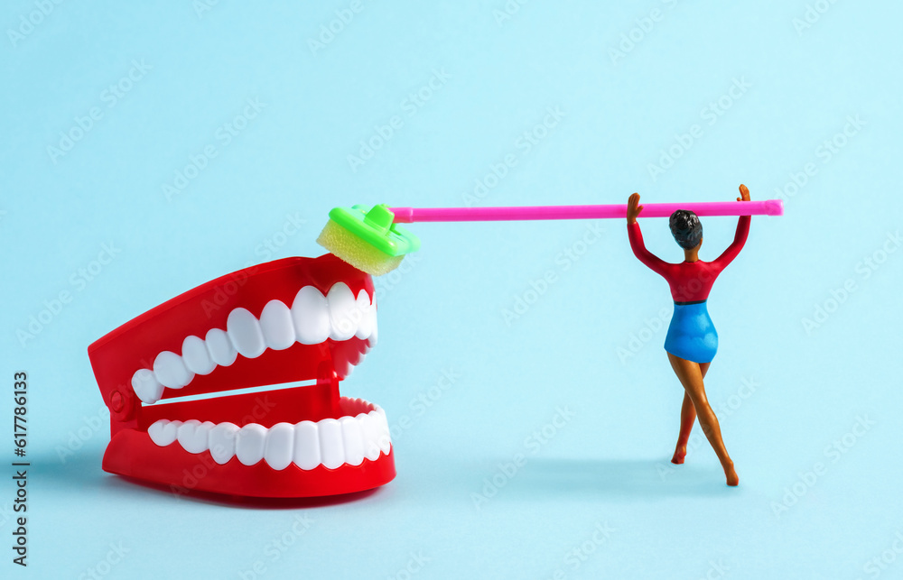 Miniature model of woman with brush cleans model of human tooth on blue ...