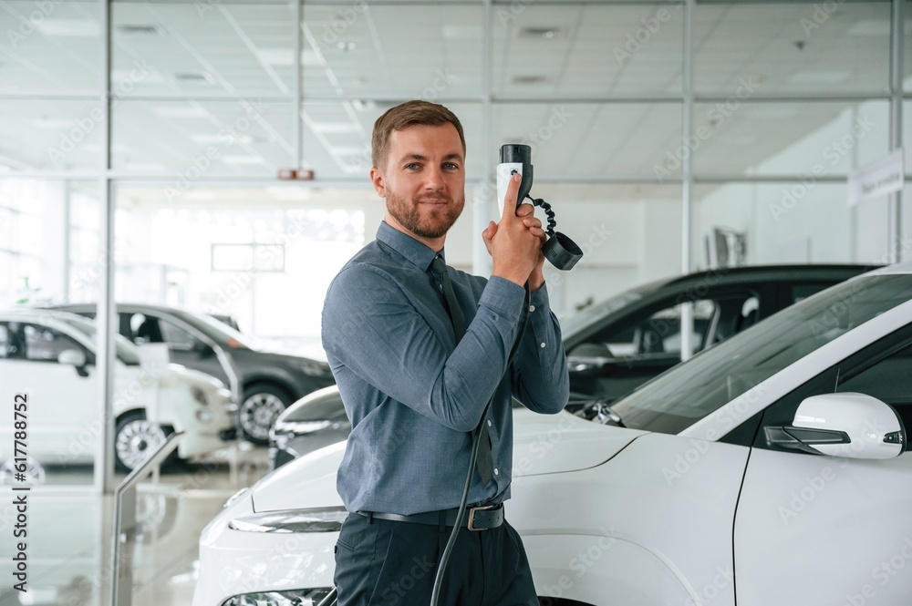 Having fun with charger. Handsome car dealership worker is with ...