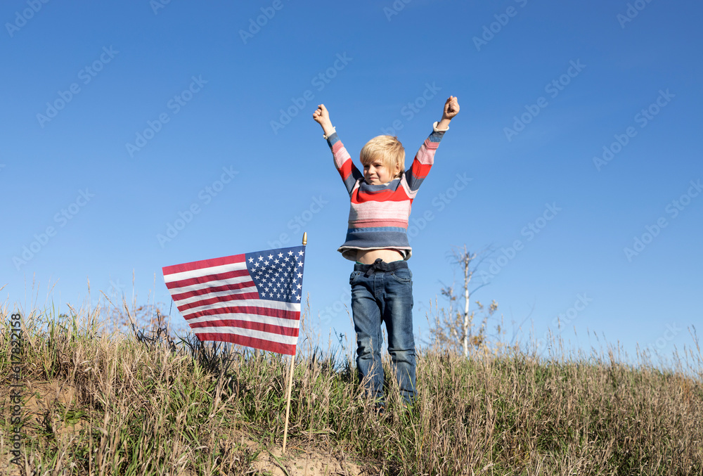 boy proudly raised his hands, an American flag stands nearby, focus on ...