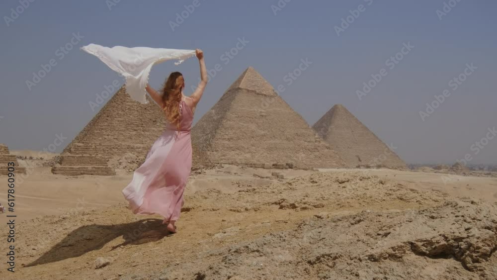 Back view of the young woman walking towards the Great Pyramids of Giza ...