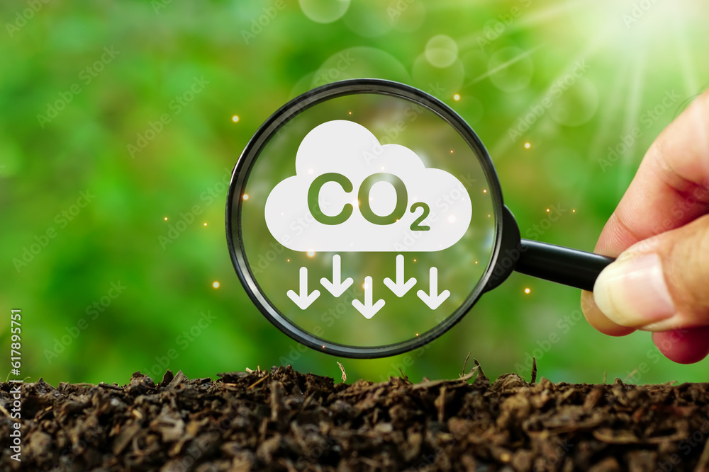 CO2 reducing icon inside magnifier glass, CO2 emission concept. Green industries business ...