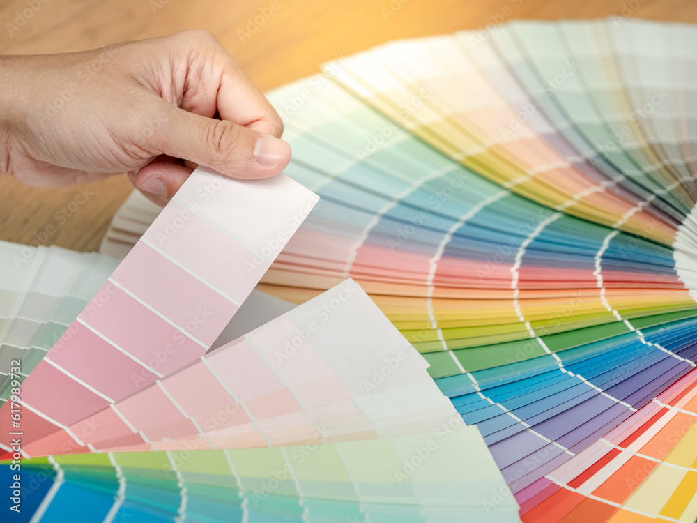 Designer hand choosing and pointing at color swatch samples catalog or ...