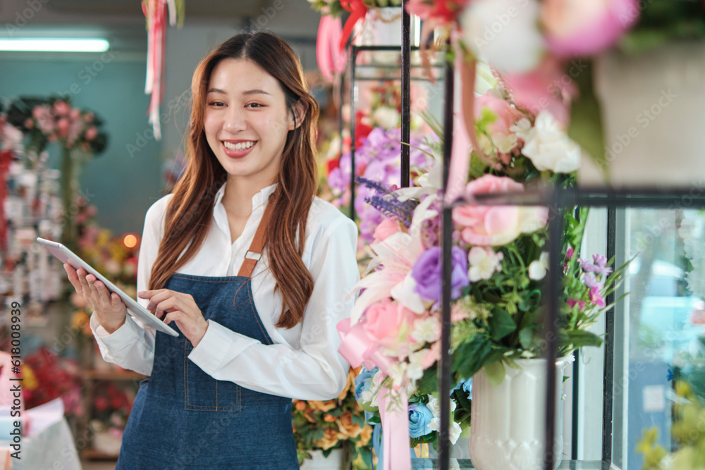 Portrait of one beautiful young Asian female florist worker in apron ...