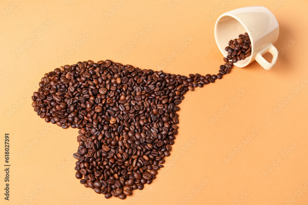 Coffee beans spilled from cup in shape of heart on orange background ...