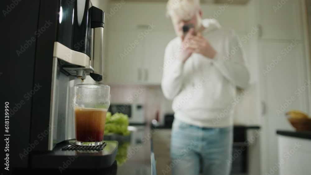 Close up of black coffee machine making coffee. Albino man appears from ...