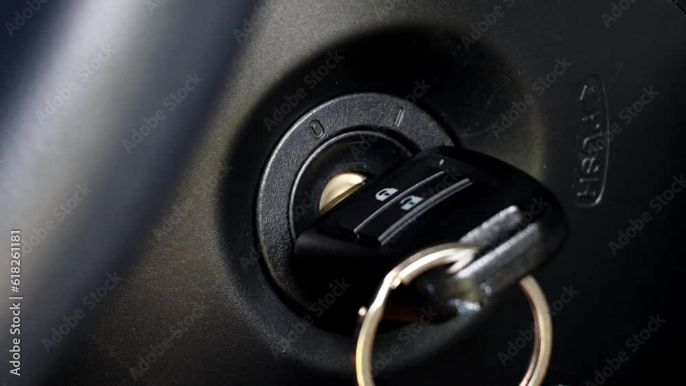 Close-up shot of a man putting his car keys into socket and starting ...