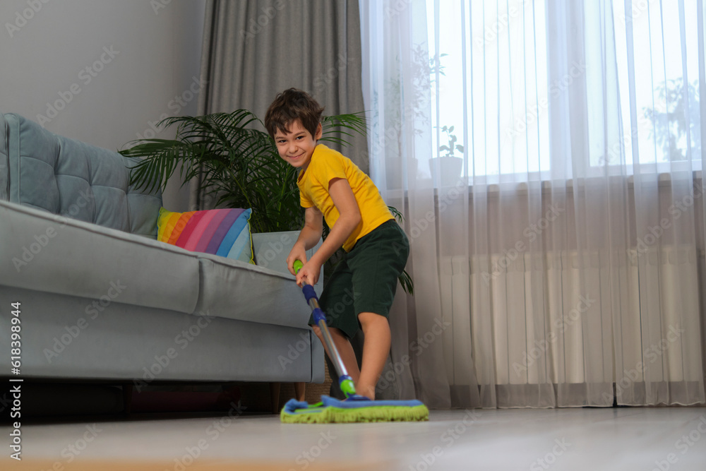 cheerful boy stands on a mop imagining that he is flying on it. fun ...