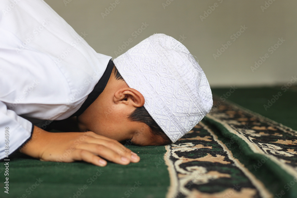 Side view of muslim boy bowing down praying to Allah in Sujud pose ...