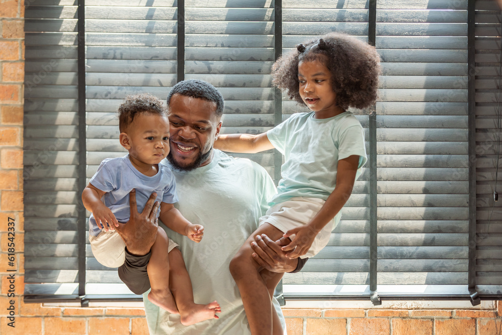 Happy african black dad father carry hold baby son and daughter on arm ...