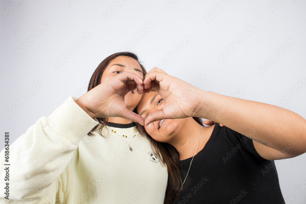 photograph of a couple of women making a heart with their hands on a ...