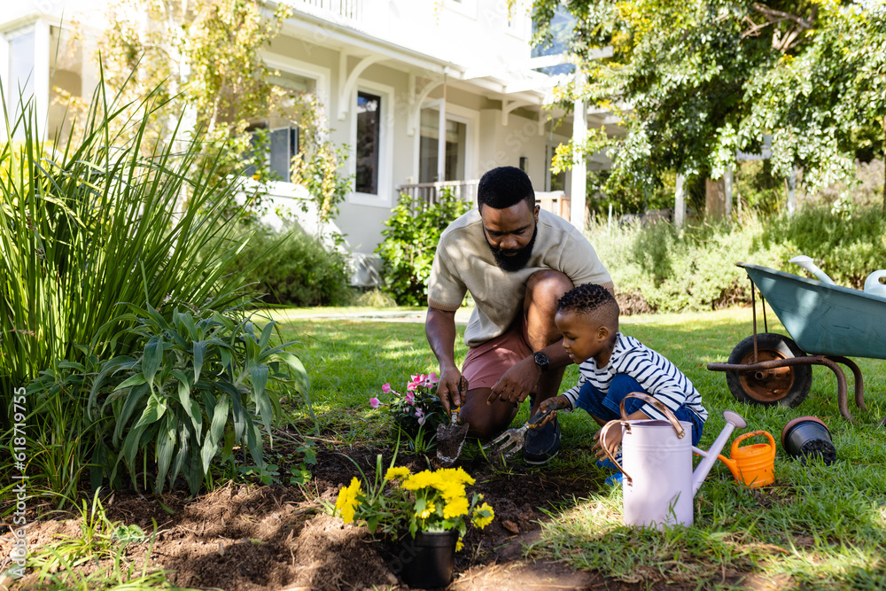African american father and son digging dirt for planting flowers on ...