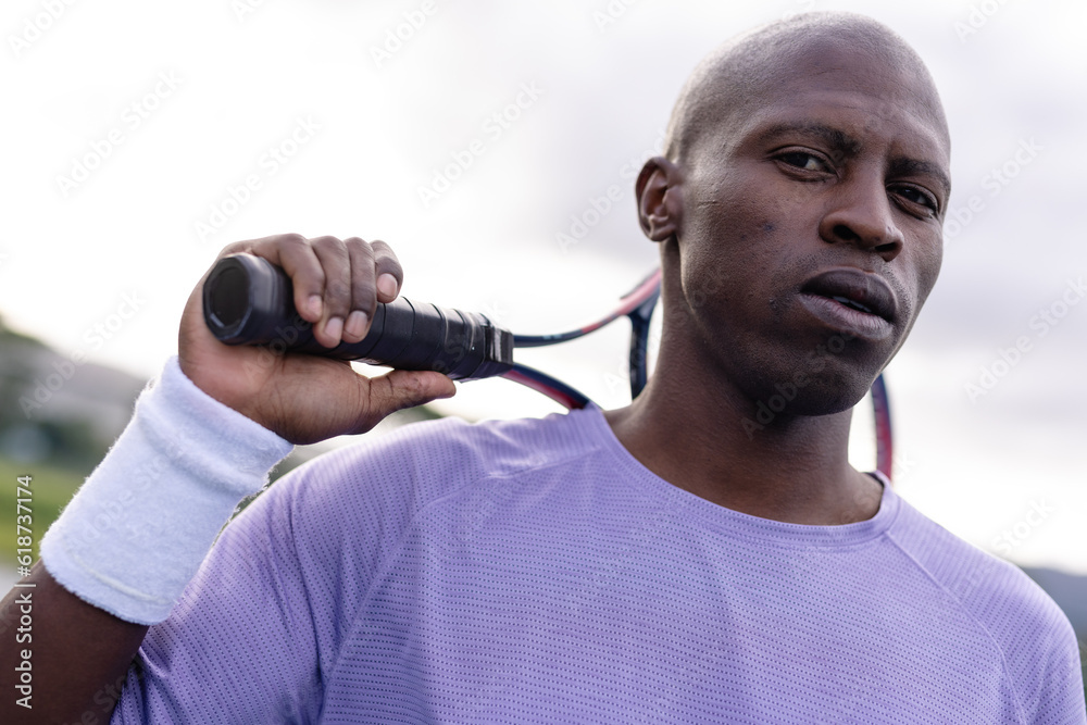 Portrait of serious african american male tennis player holding tennis ...
