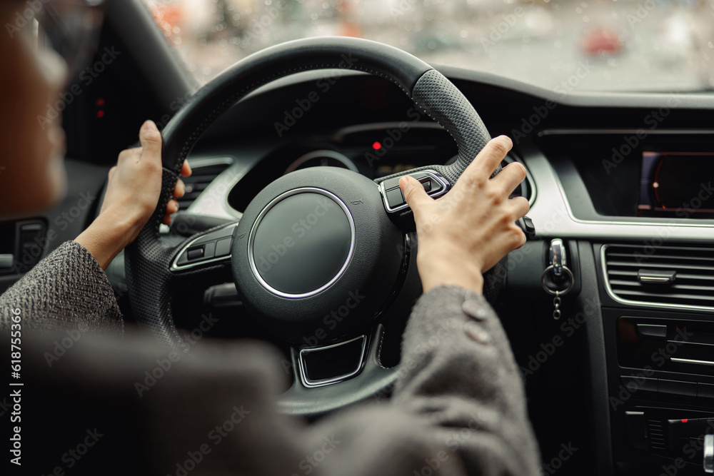 Back view of woman driver pushes the button on steering wheel during ...