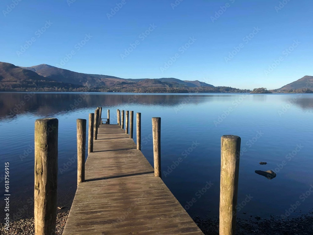 wooden pier extending over a body of water in front of mountains Stock ...