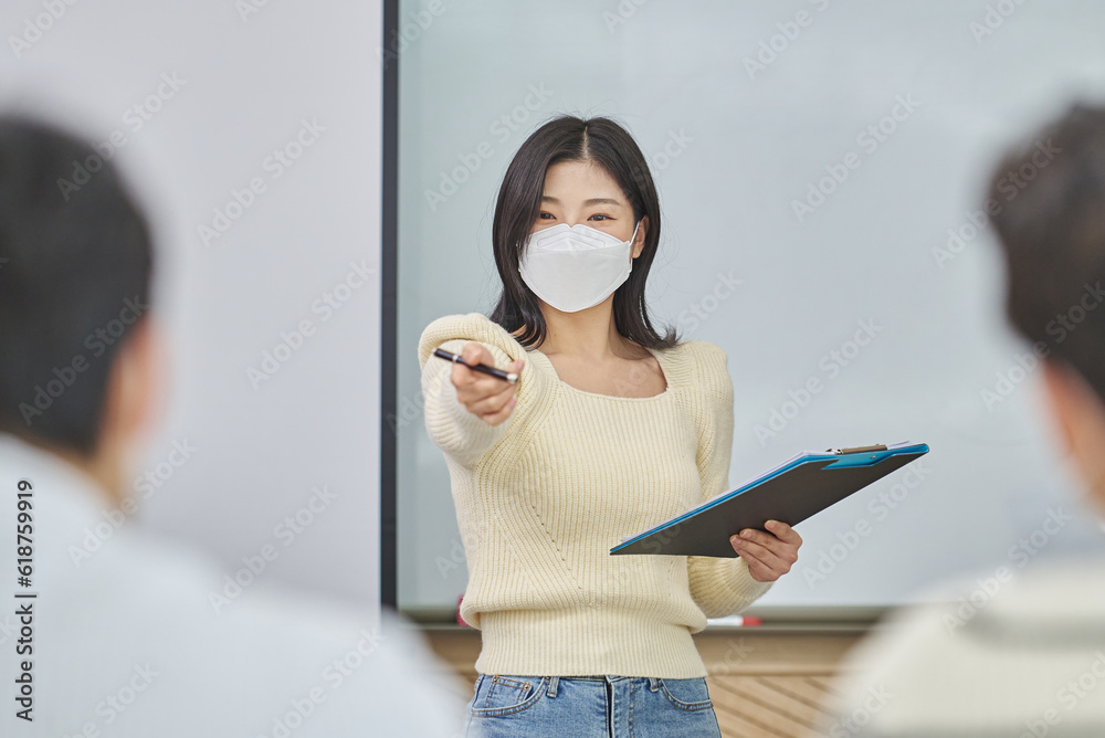 An Asian female student or professor is wearing a mask and standing in ...
