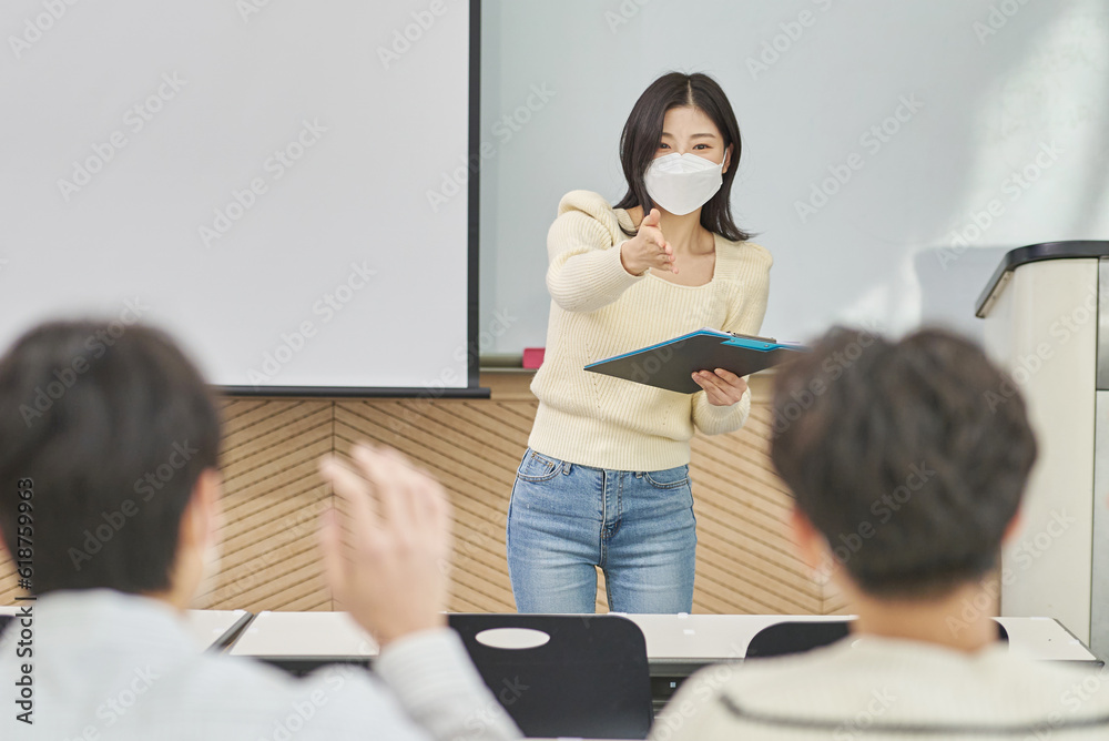An Asian female student or professor is wearing a mask and standing in ...