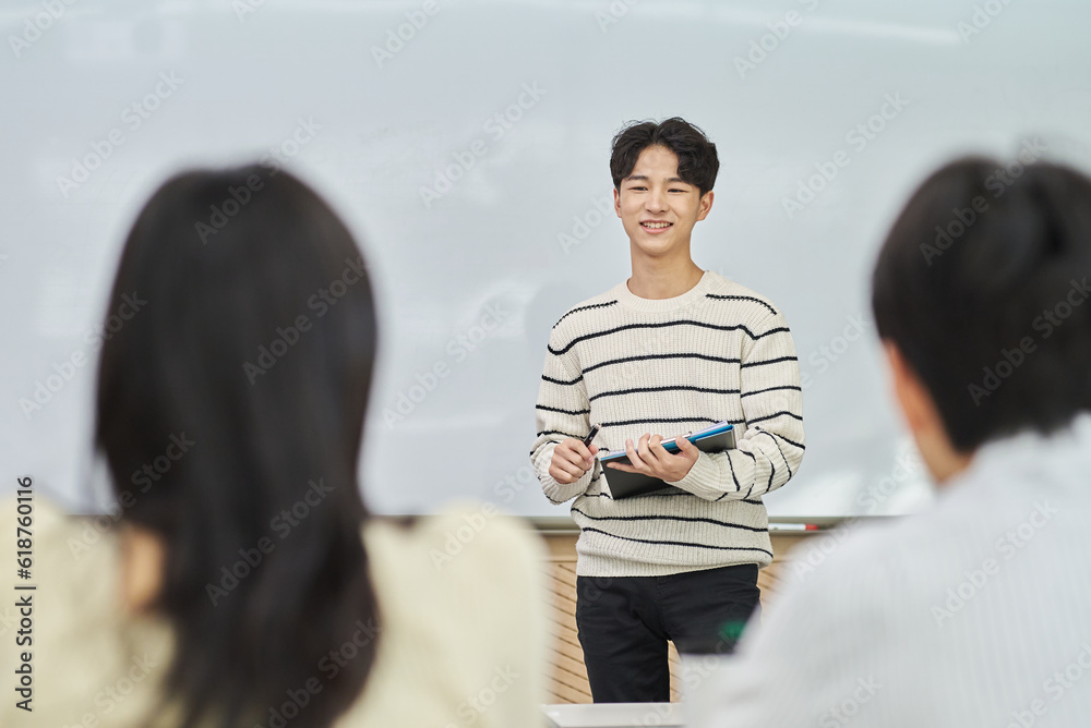 An Asian young man is standing in front of a lecture hall at a ...