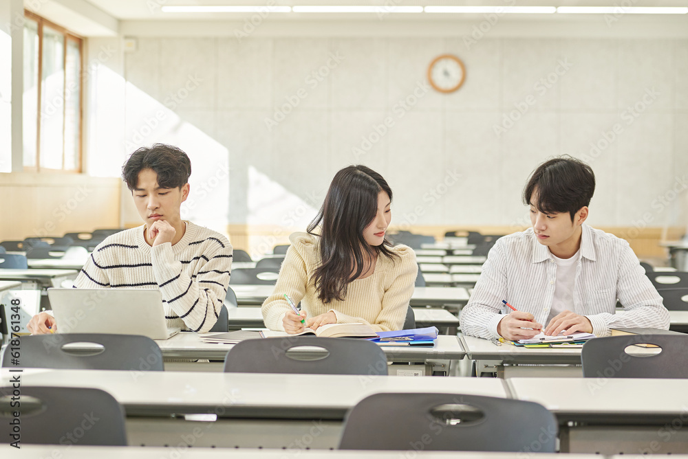 Three young Asian college students, both male and female, are in a ...