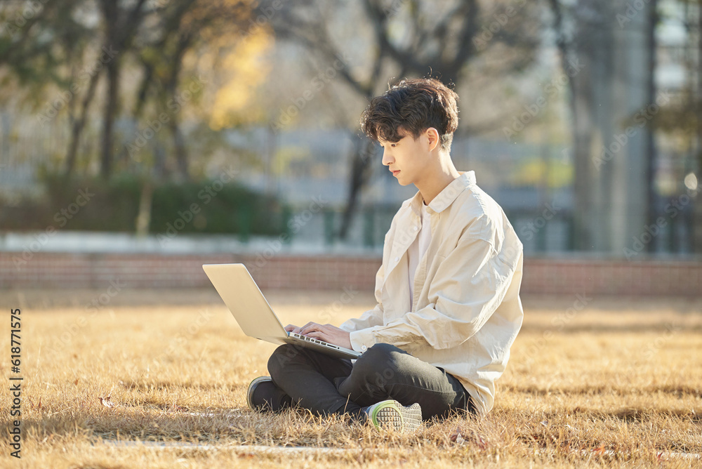 Young and attractive college student male model sitting on lawn at ...