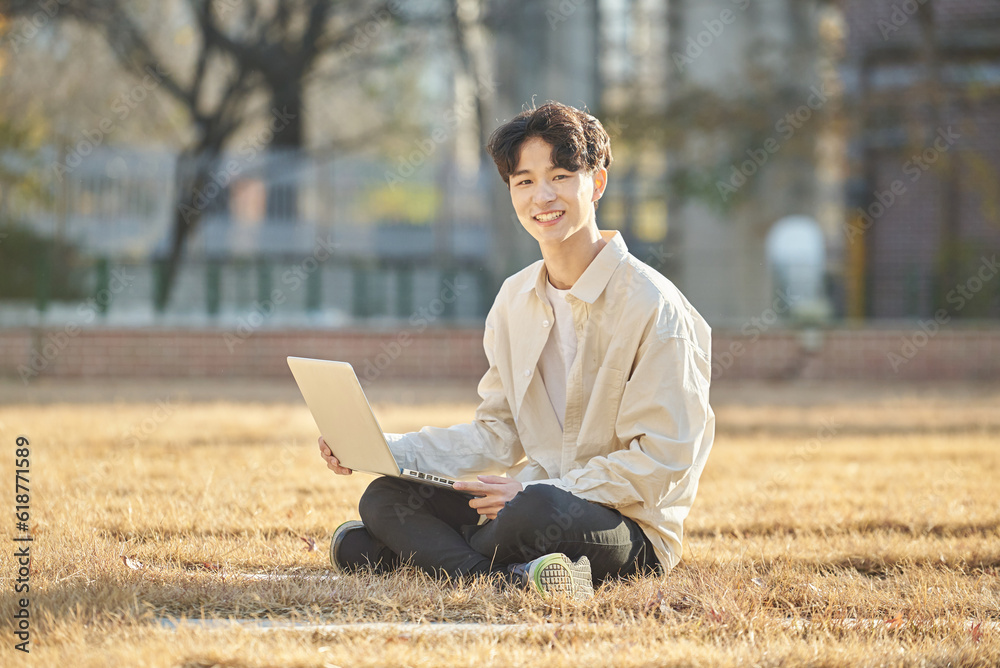 Young and attractive college student male model sitting on lawn at ...