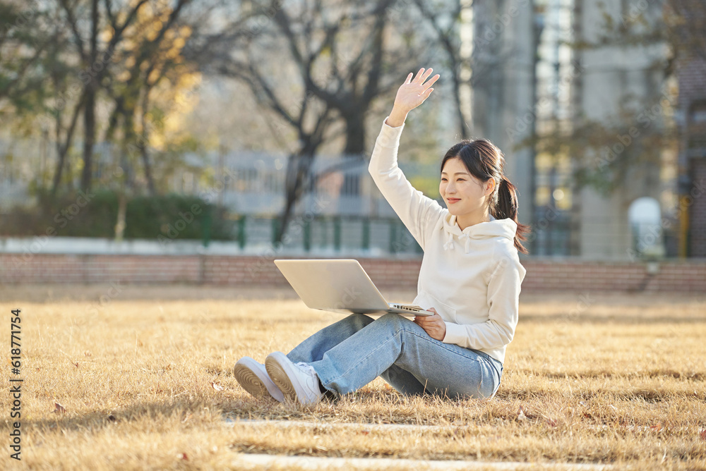 Young and attractive college student female model sitting on lawn in ...