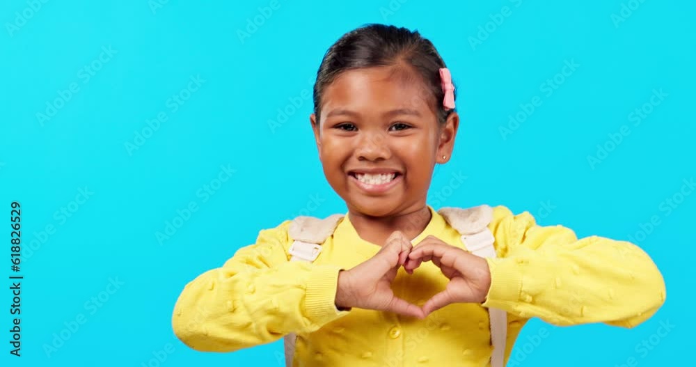 Portrait, girl with heart hand sign and against blue background with ...