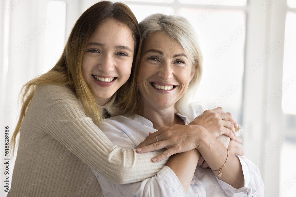 Happy beautiful teenage girl and mature pretty grandma posing indoors ...