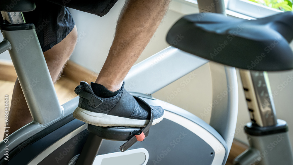 Close up of male feet in sport footwear cycling on an upright ...