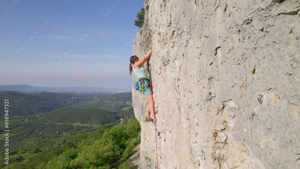 AERIAL: Sporty woman climbing a limestone wall above amazing Karst ...
