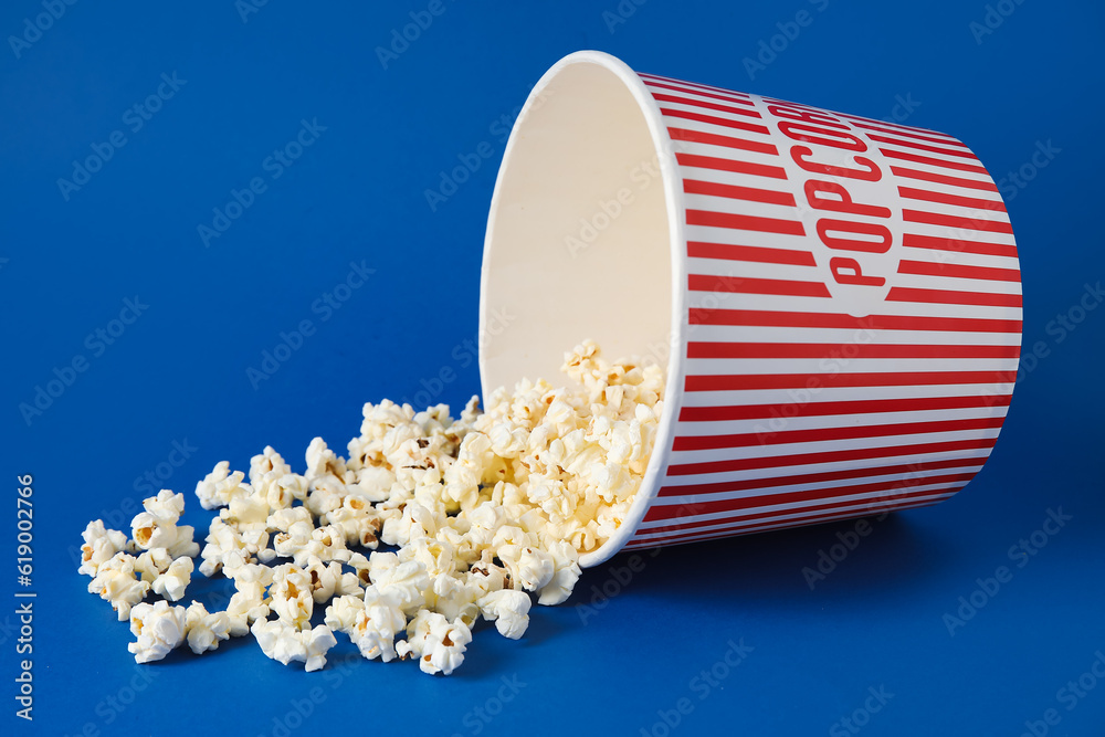 Bucket with tasty popcorn on blue background Stock Photo | Adobe Stock