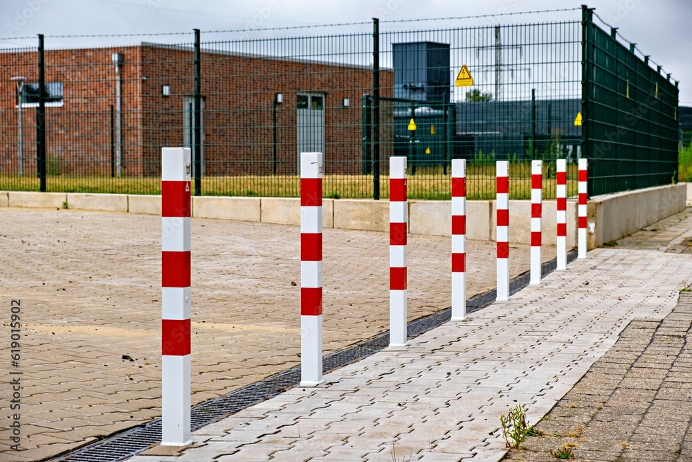 A row of red and white bollards forbidding entry and standing next to ...